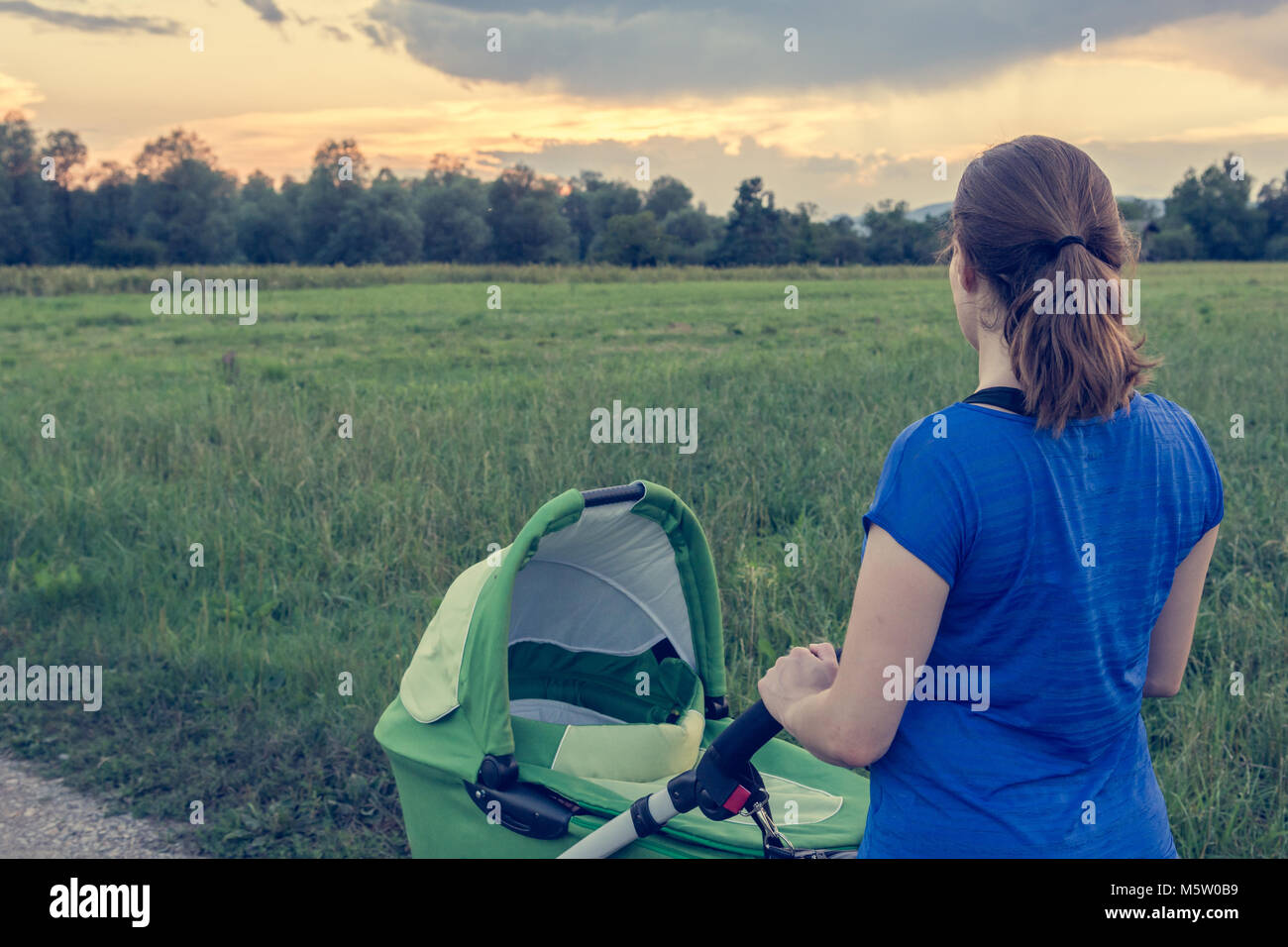 Active mom pushing a stroller at sunset Stock Photo - Alamy