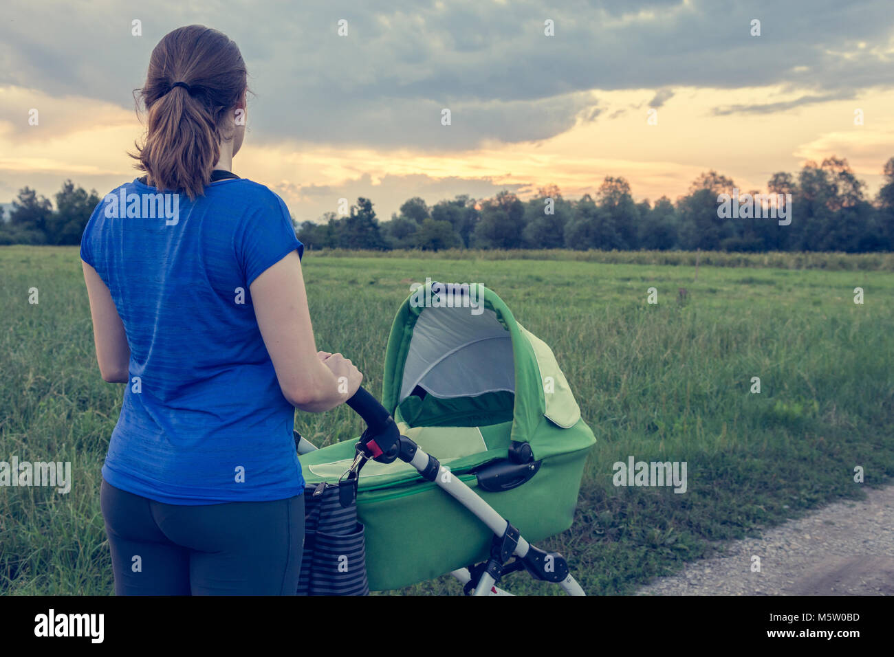 Active mom pushing a stroller at sunset Stock Photo - Alamy