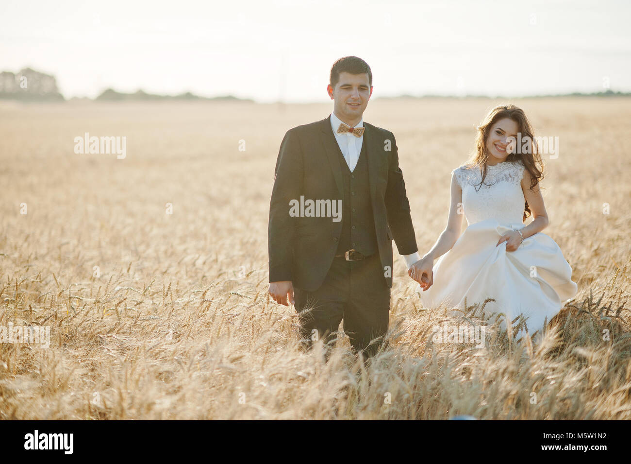 Loving wedding couple at field of wheat Stock Photo - Alamy