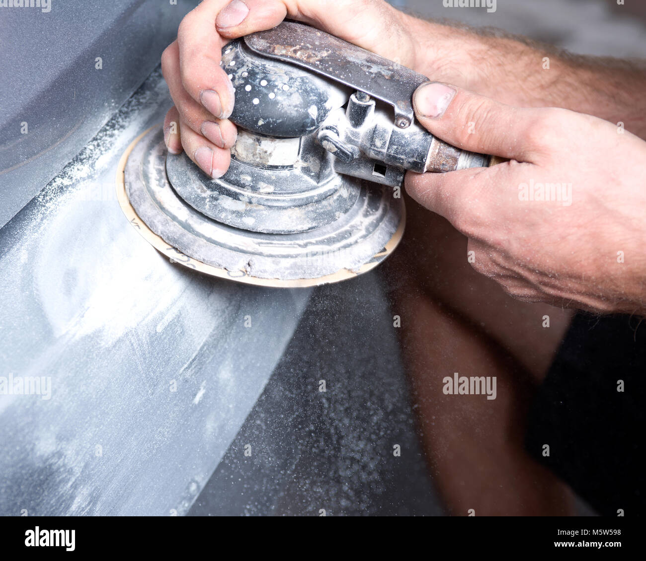 Worker is sanding filler with air sander in auto body shop Stock Photo ...