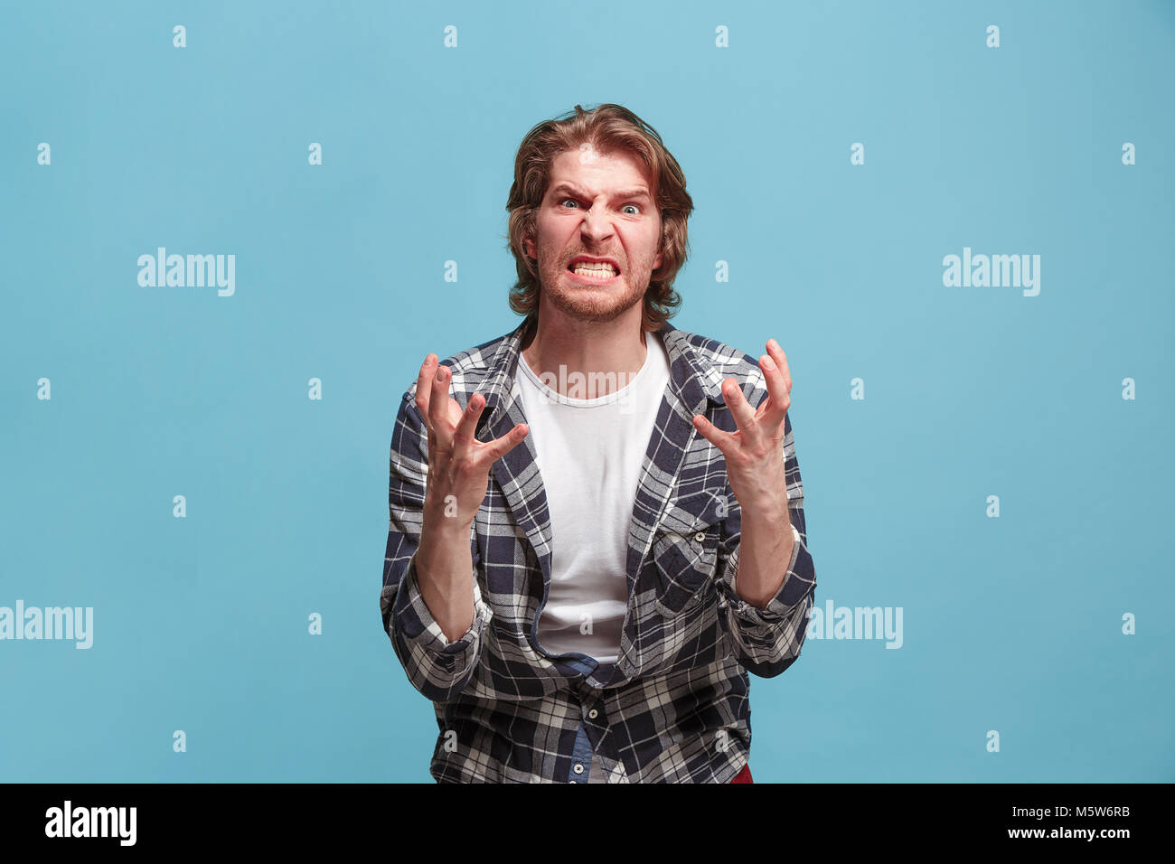 Portrait of an angry man looking at camera isolated on a blue ...