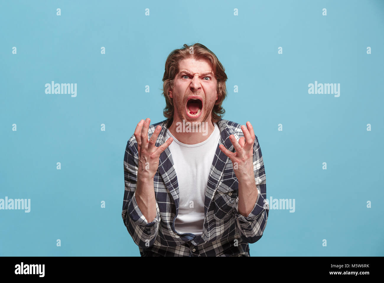 The young emotional angry man screaming on blue studio background Stock ...