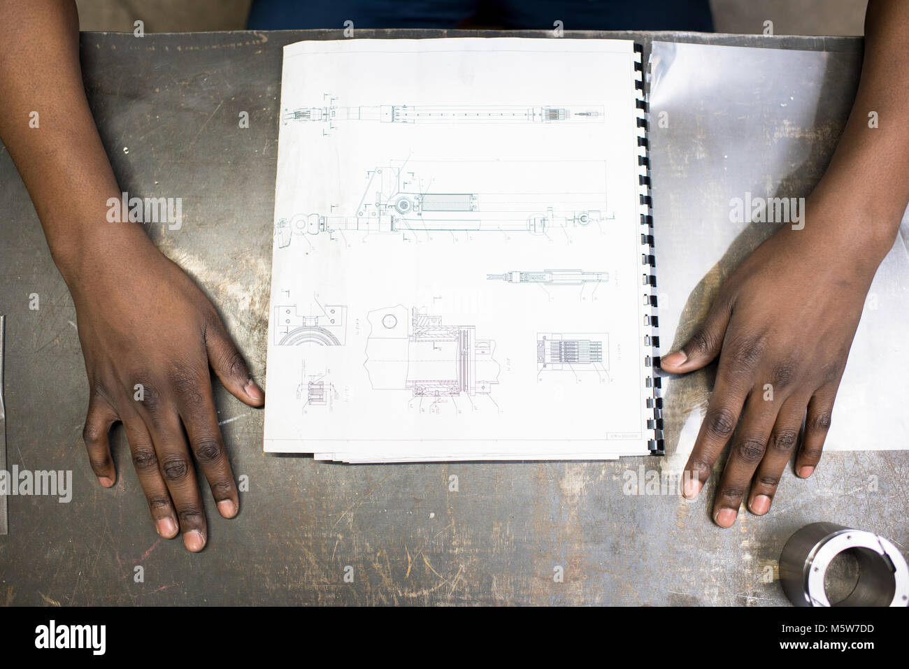 Directly above view of unrecognizable lathe operator sitting at work ...