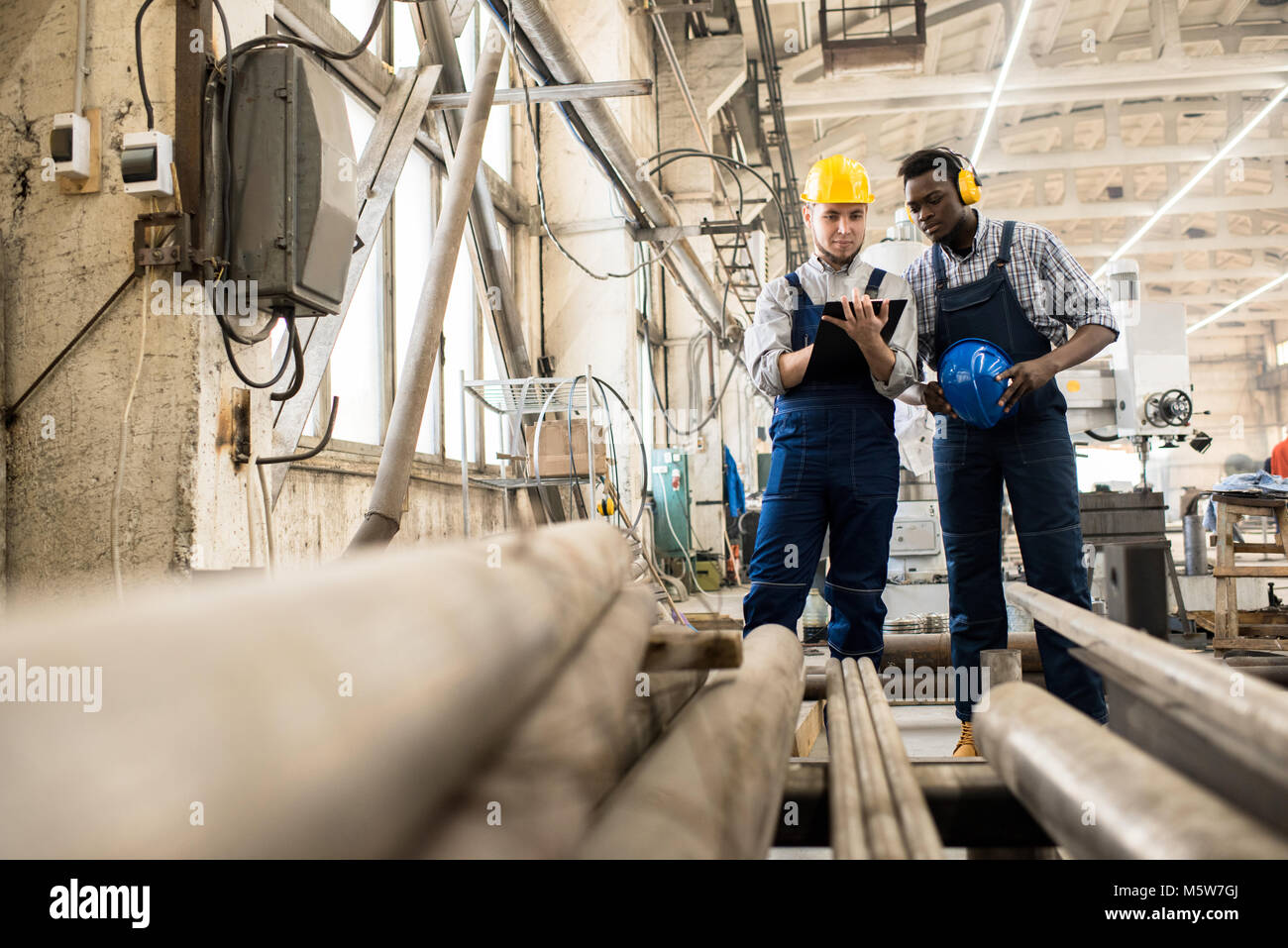 Multi-ethnic team of inspectors wearing overalls and hardhats standing ...