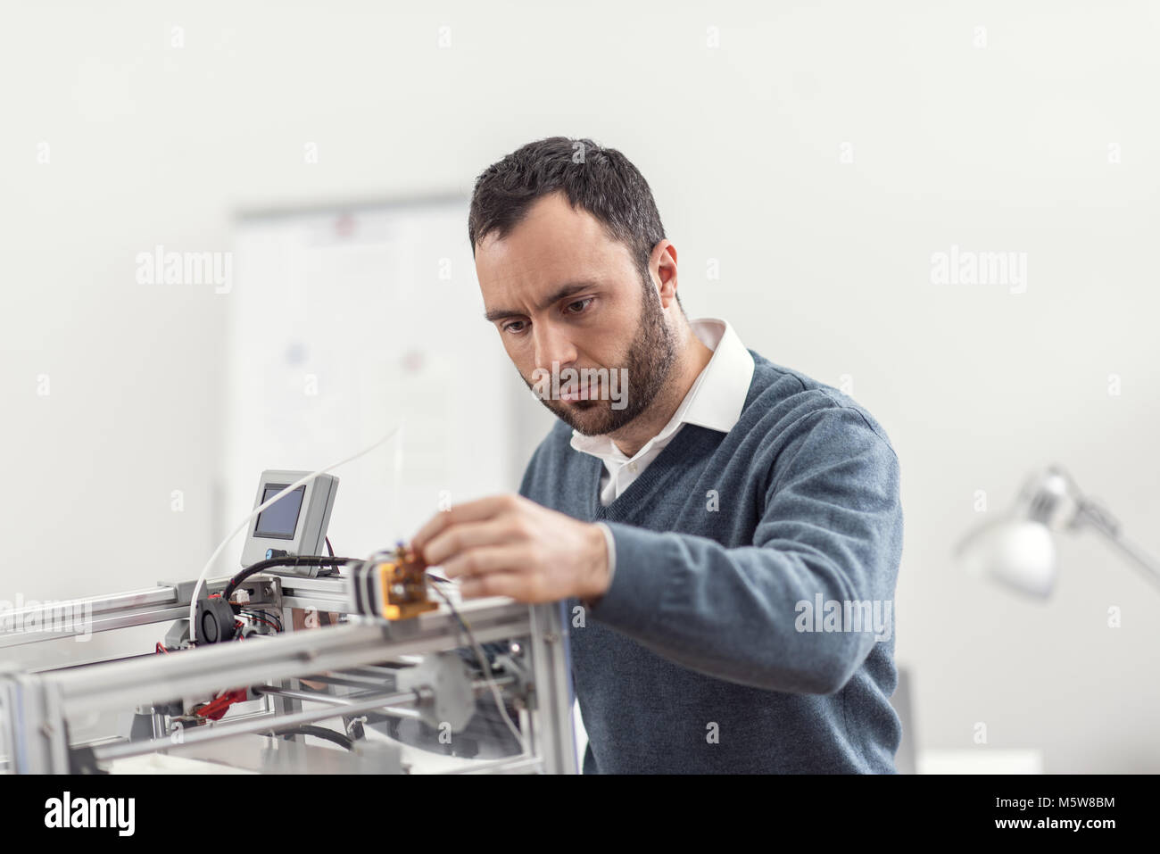 Serious young engineer getting 3D printer ready for work Stock Photo ...