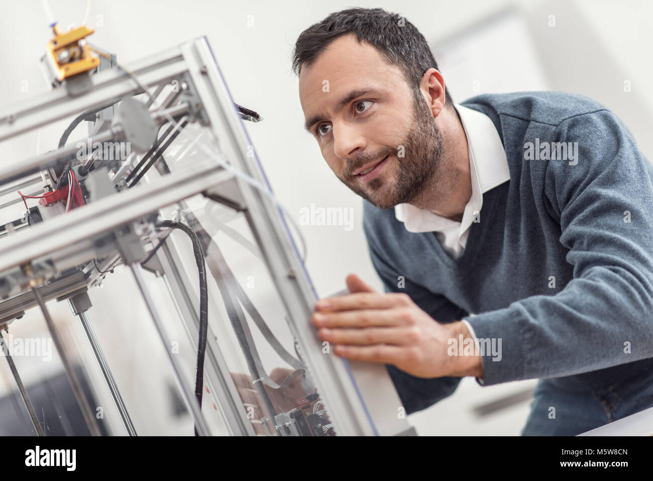 Pleasant young engineer moving 3D printer Stock Photo - Alamy