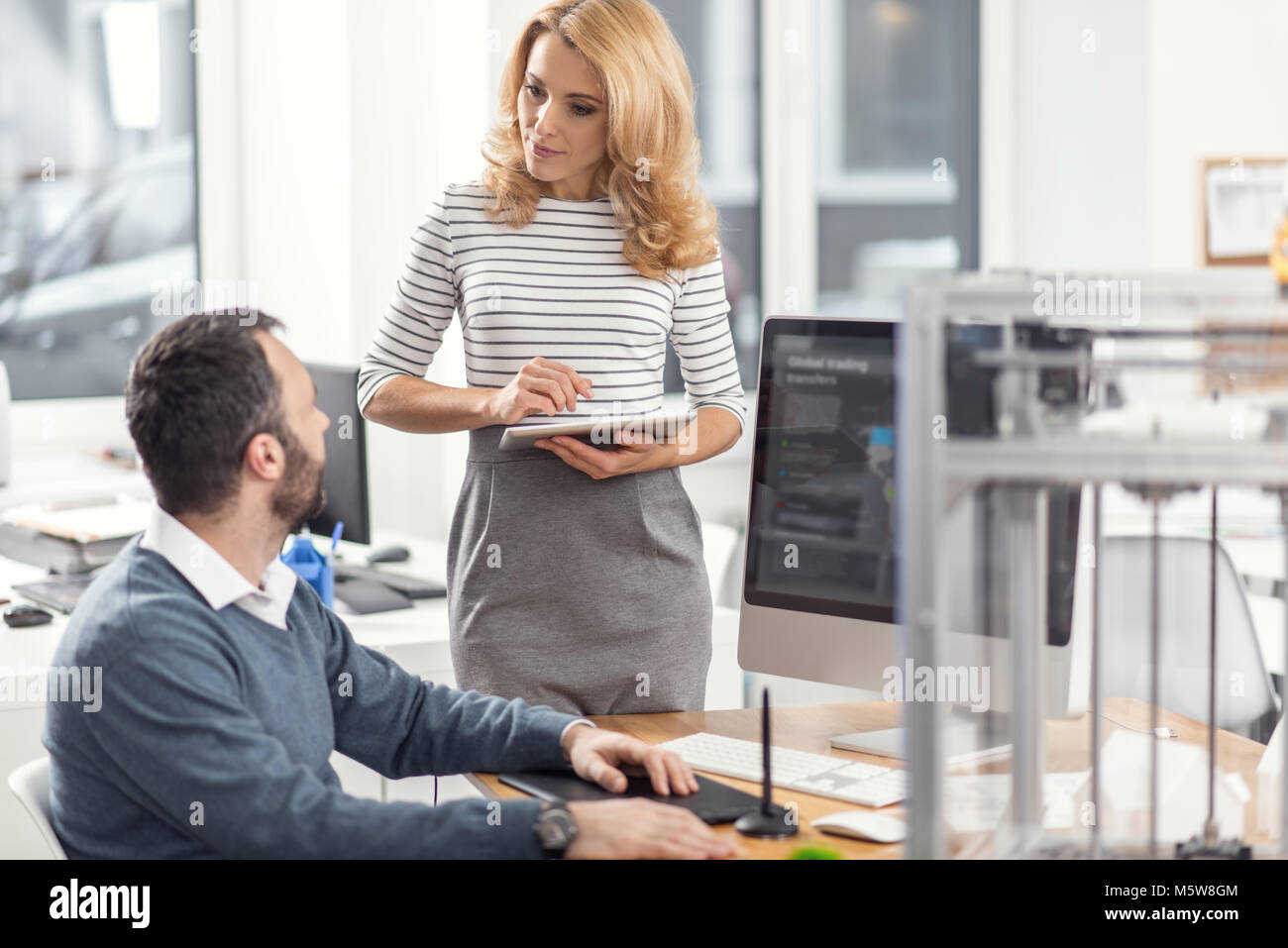 Female supervisor listening to her colleagues report and making notes ...