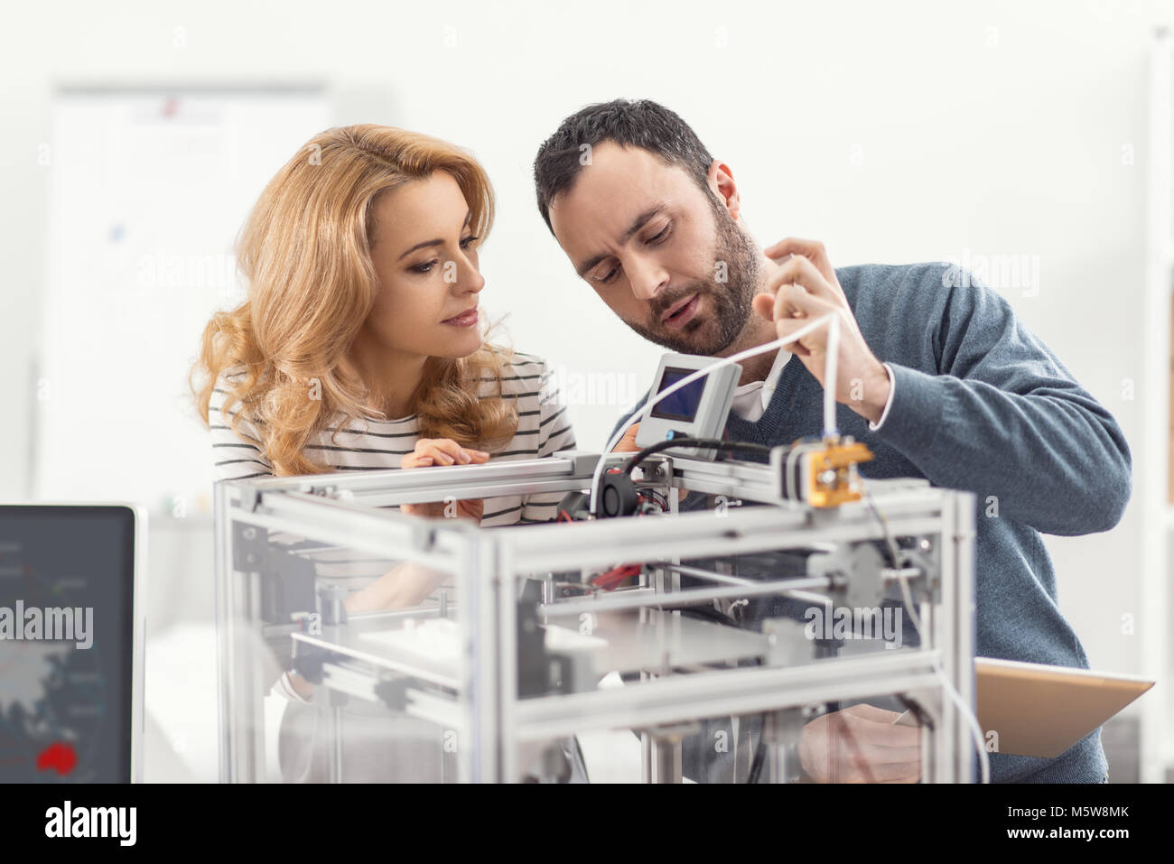 Pleasant man teaching his colleague how to use 3D printer Stock Photo ...