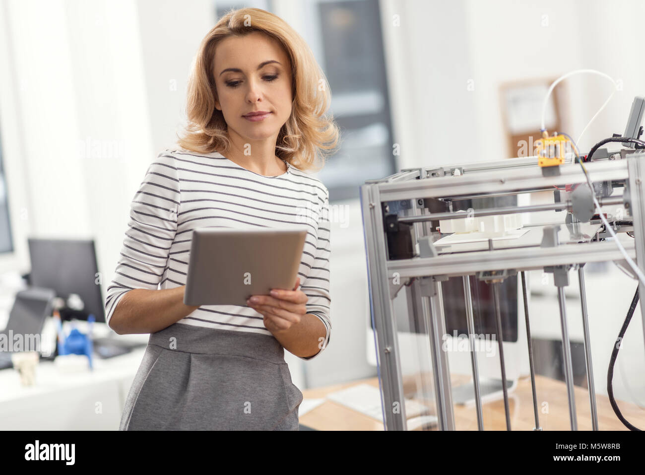 Beautiful woman using her tablet while 3D printer working Stock Photo ...