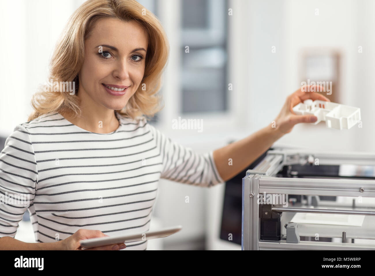 Pretty woman posing while holding printed model Stock Photo - Alamy