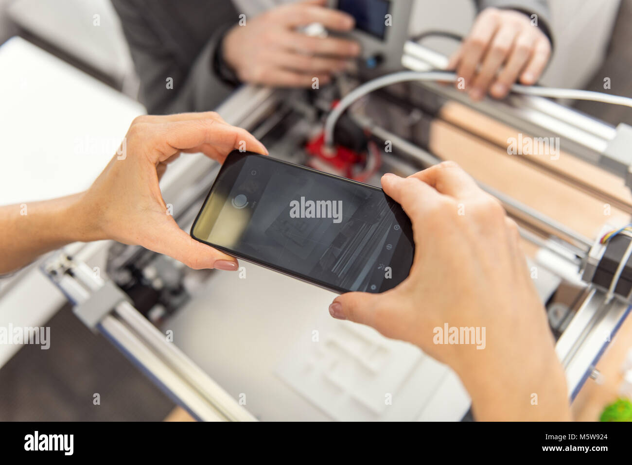 Female hands taking photo of 3D printer creating model Stock Photo - Alamy