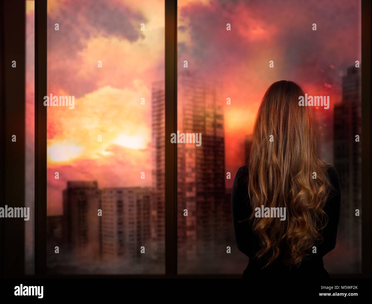 The girl looks through the window at the burning city. Concept - war ...