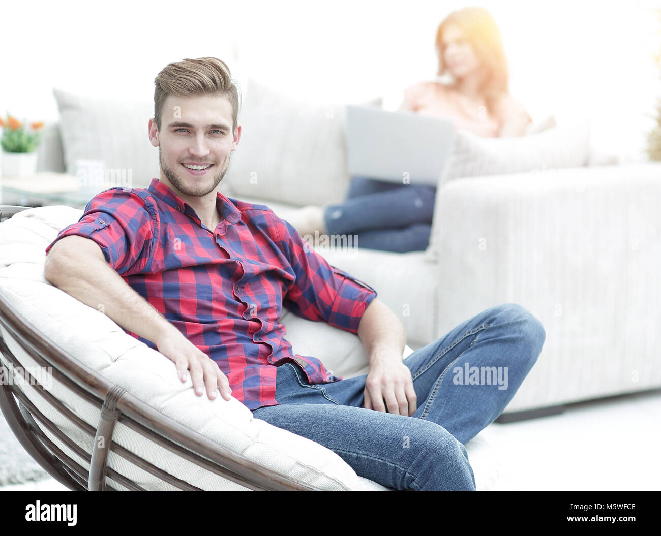 smiling young male sitting in a big chair Stock Photo - Alamy