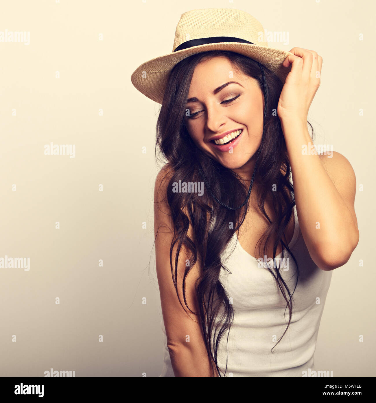 Beautiful long hair laughing woman in white top and straw hat looking happy. Toned vintage ...