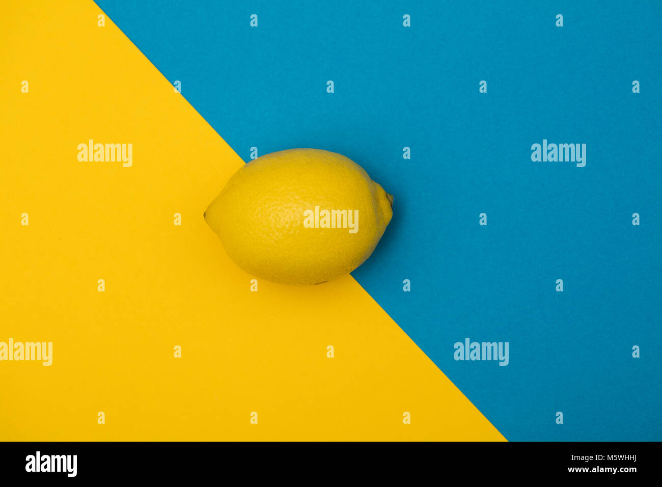 Yellow lemon on a blue and yellow background Stock Photo - Alamy