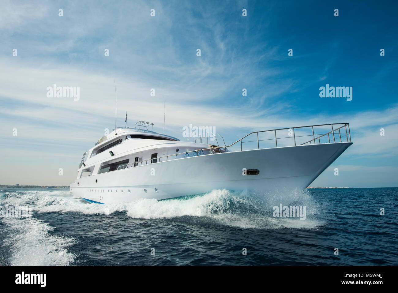 A luxury private motor yacht under way on tropical sea with bow wave ...