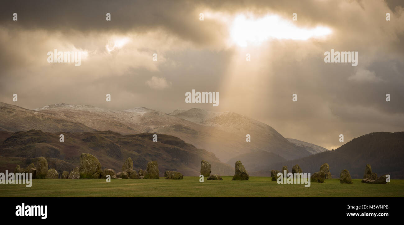 A shaft of light splits through the overcast sky behind Castlerigg ...