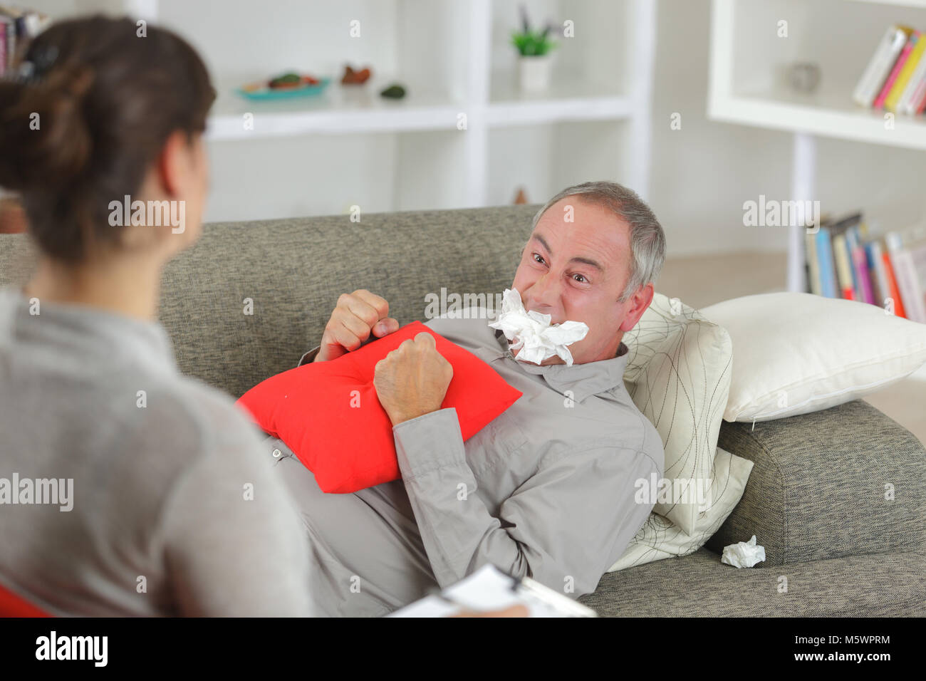 angry man sitting on sofa with psycologist Stock Photo - Alamy