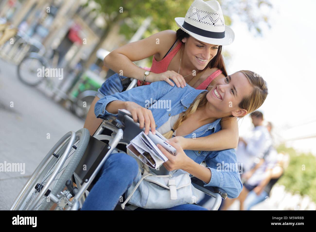 two friends visiting foreign city one sitting in wheelchair Stock Photo ...