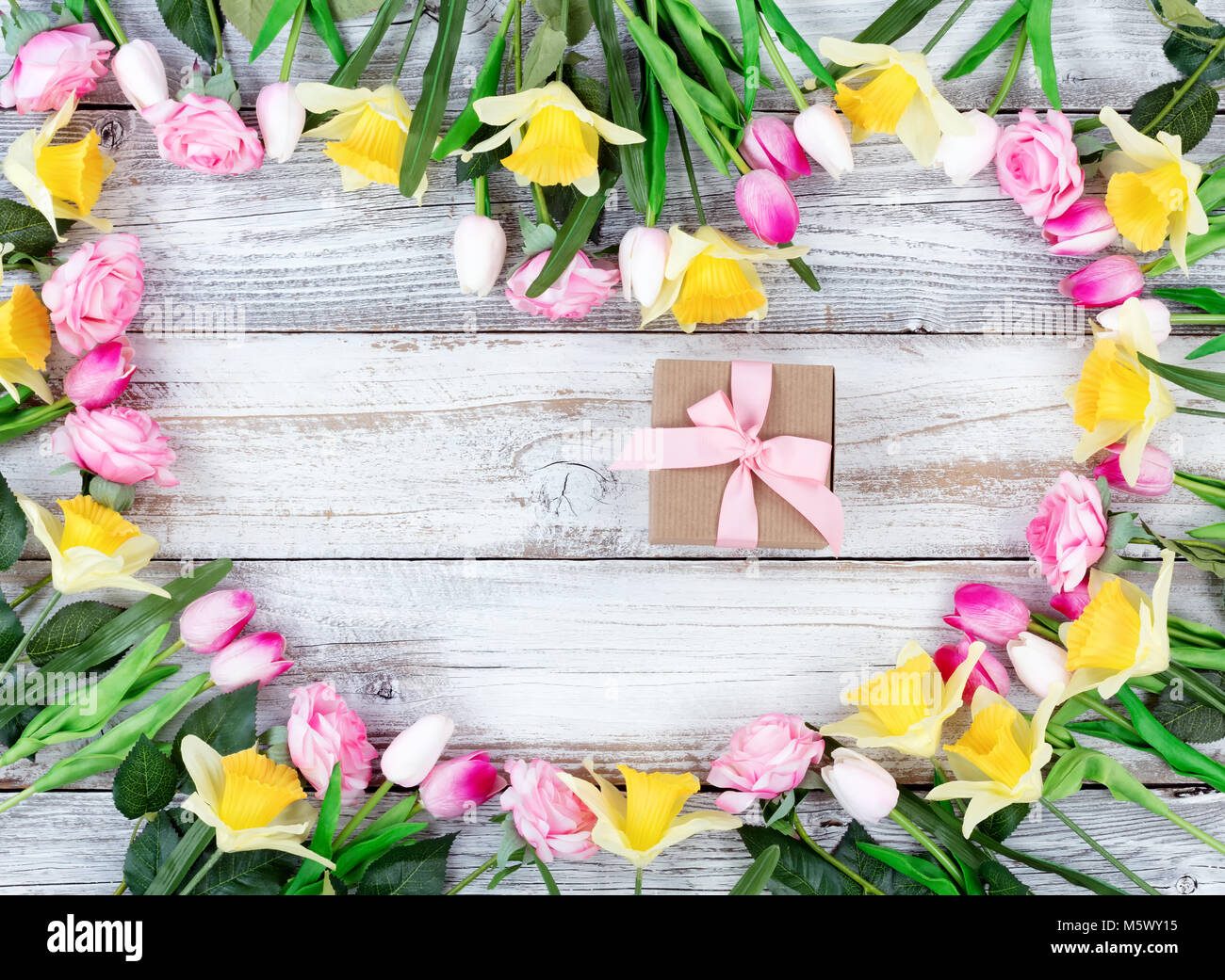 Assortment of spring flowers forming heart shape with boxed gift on ...