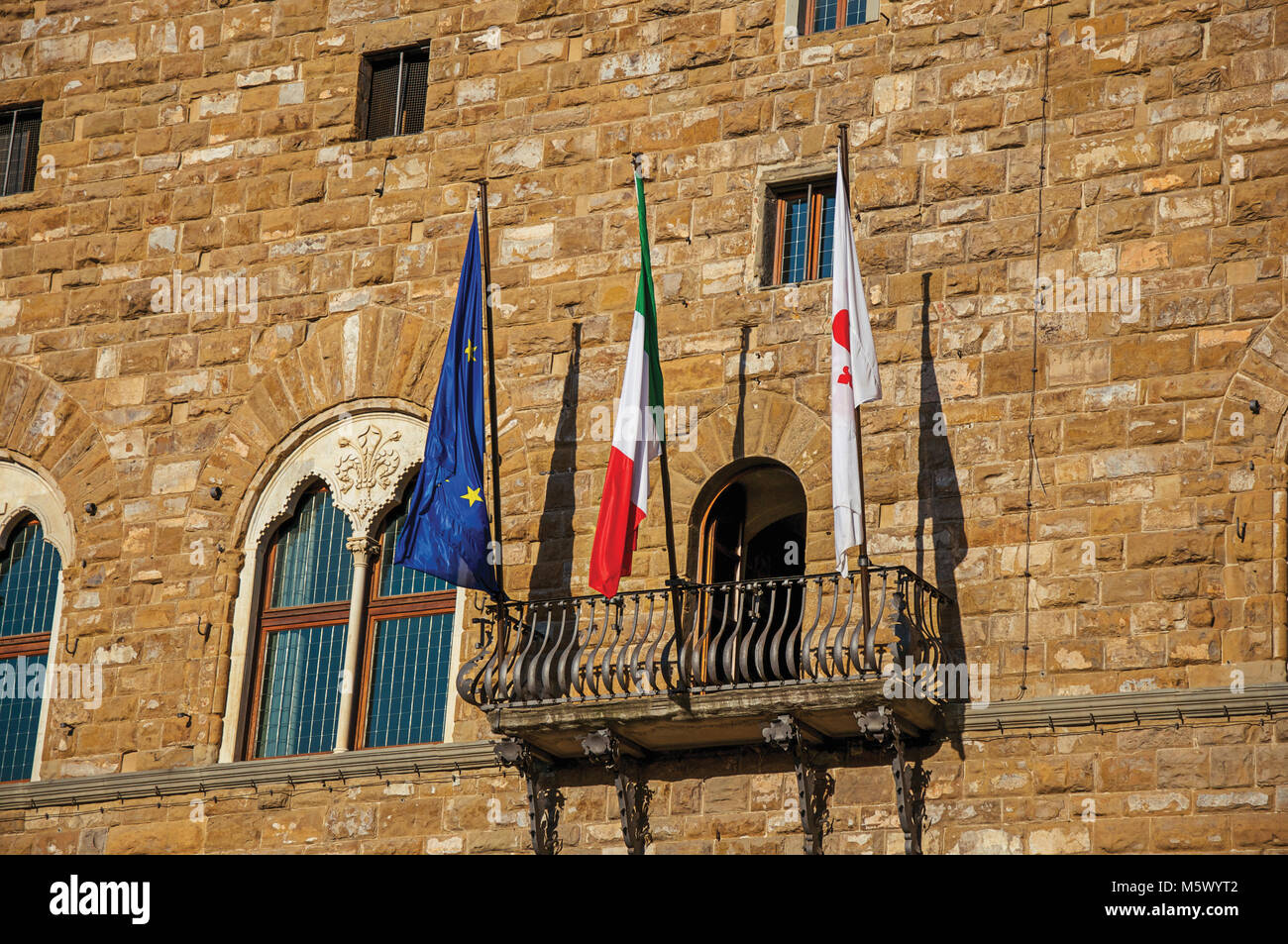 Flags on a balcony in front of the Palazzo Vecchio at sunset. In the ...