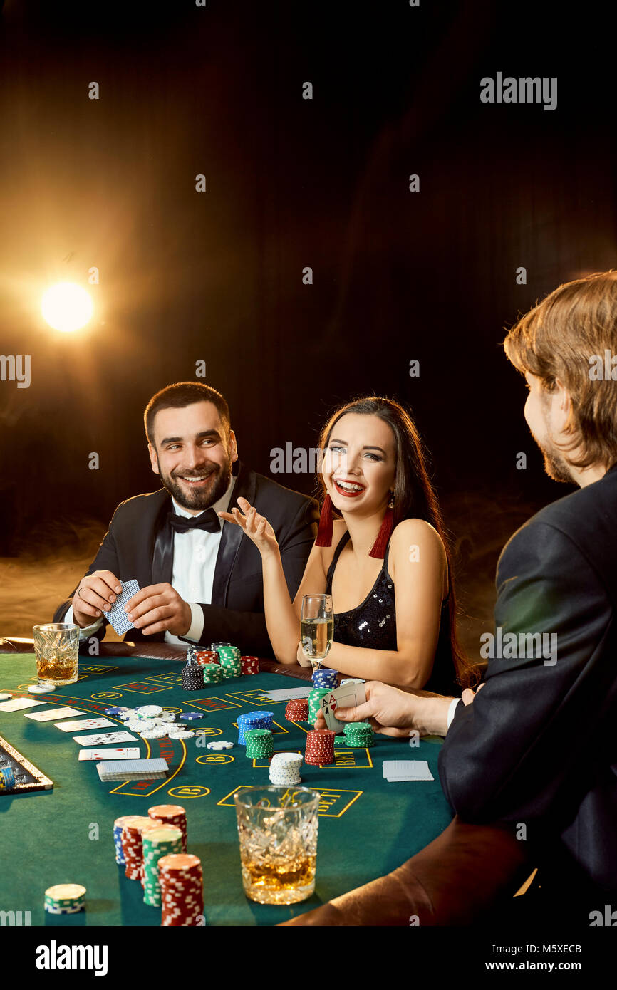 Group of young rich people is playing poker in the casino. Two men in ...