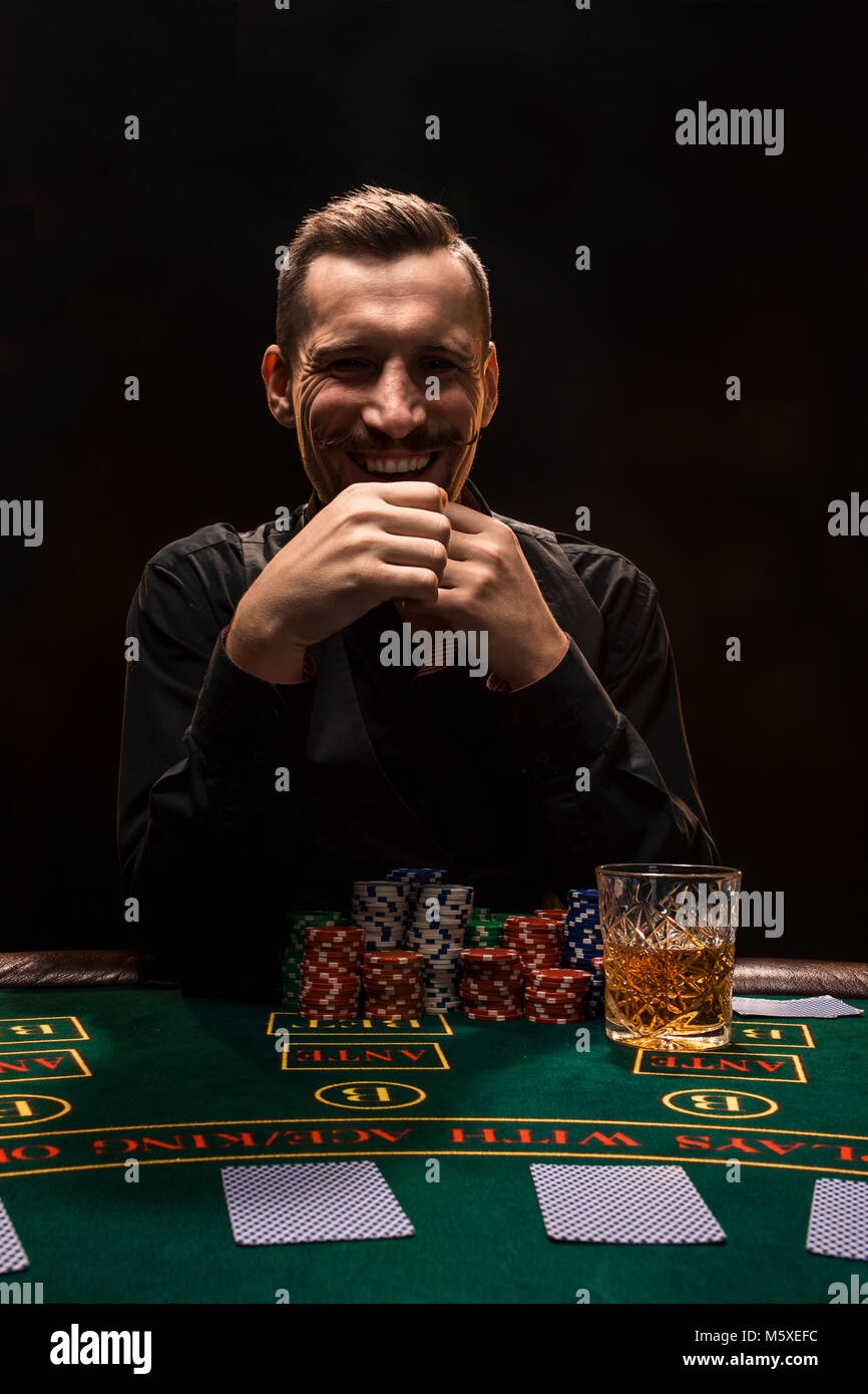 Man is playing poker with a cigar and a whiskey. A man winning all the ...