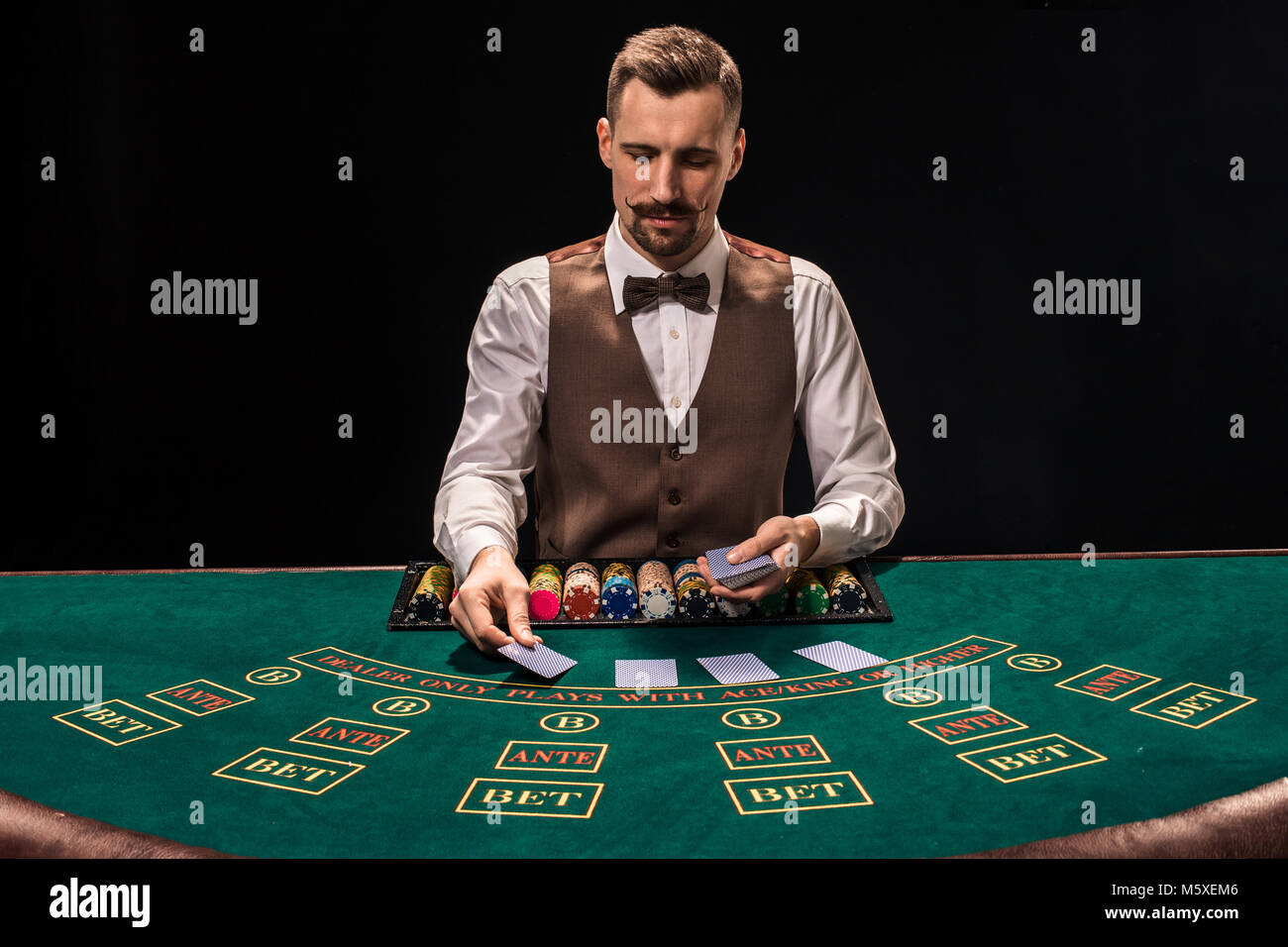 Portrait of a croupier is holding playing cards, gambling chips on ...