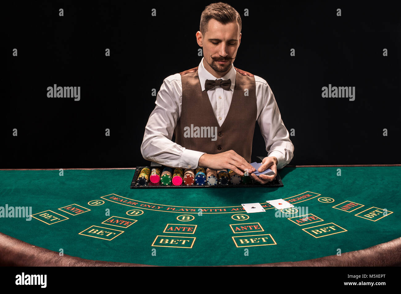 Portrait of a croupier is holding playing cards, gambling chips on ...