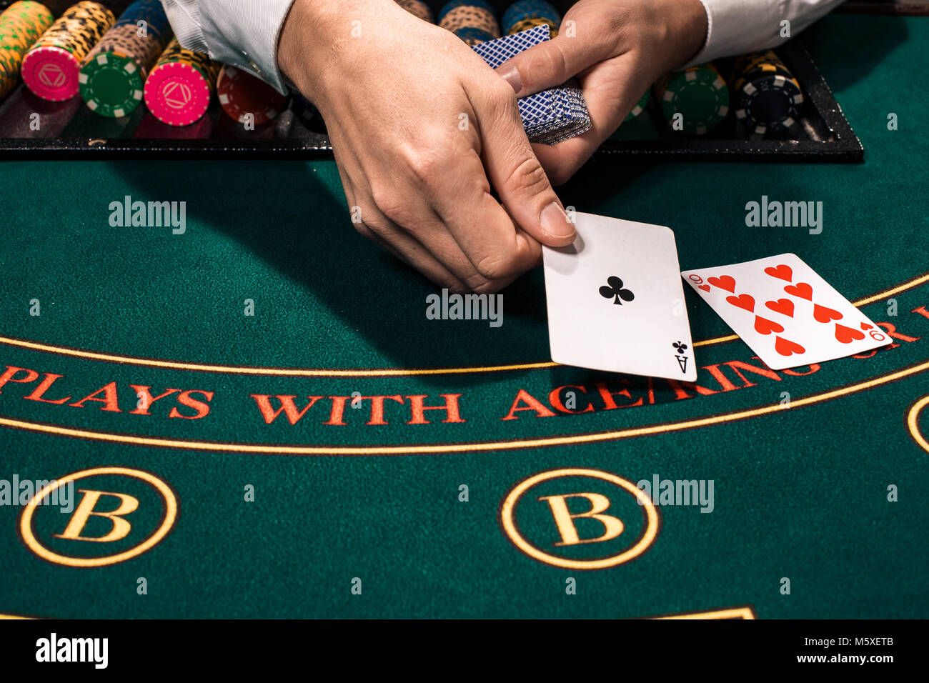 Close up of holdem dealer with playing cards and chips on green table ...