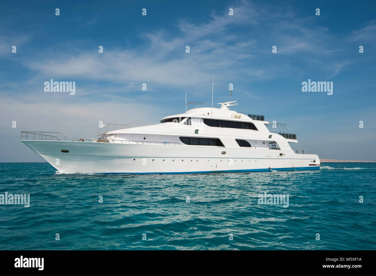 A luxury private motor yacht under way on tropical sea with bow wave ...