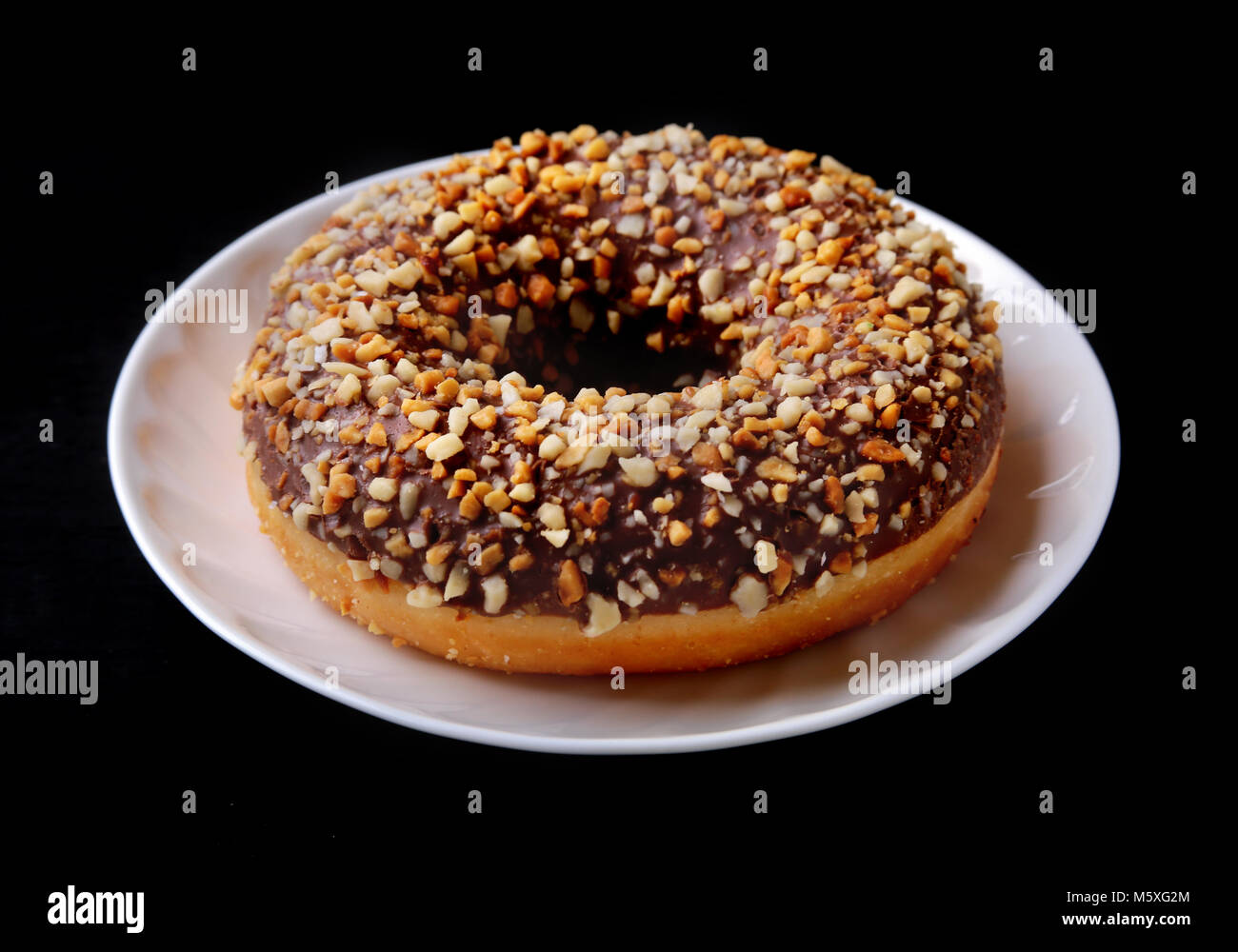 Homemade doughnuts in the glaze, colorful sprinkles and nuts on a black ...