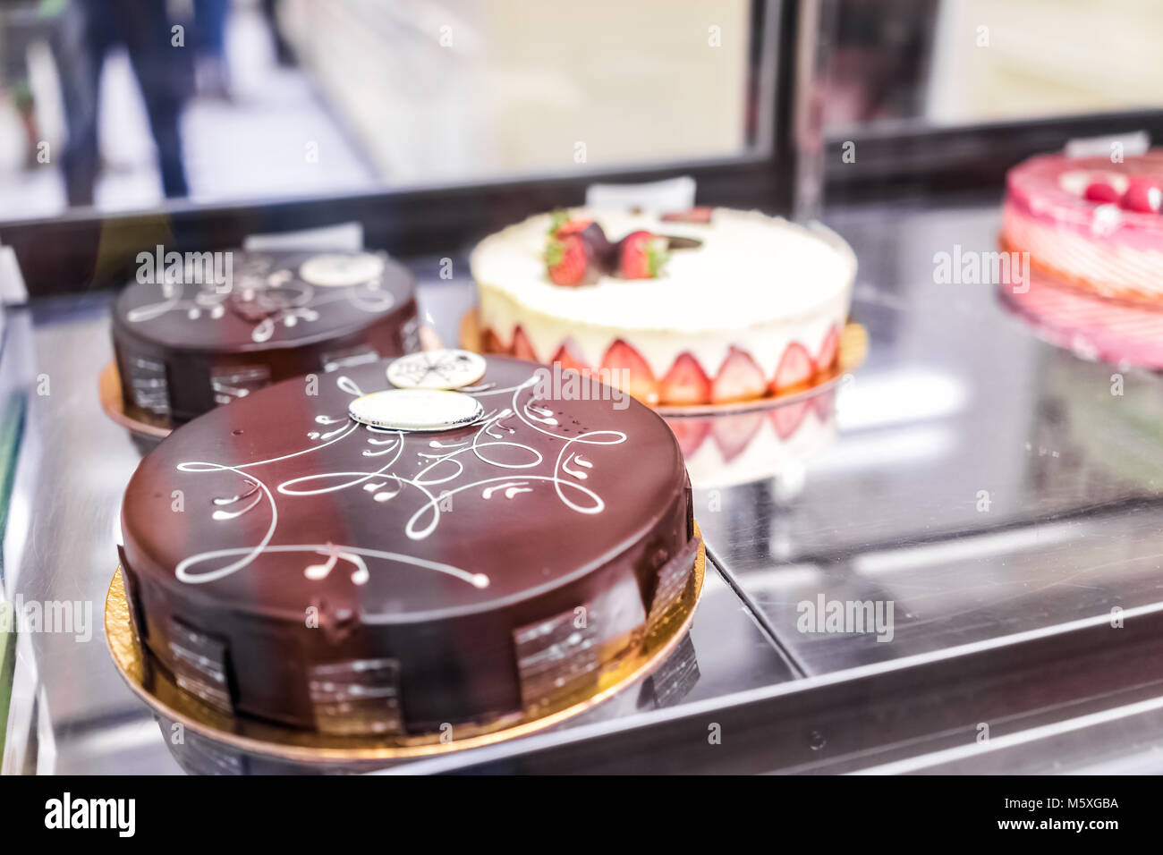 Many chocolate cakes on display in bakery shop store with strawberry ...