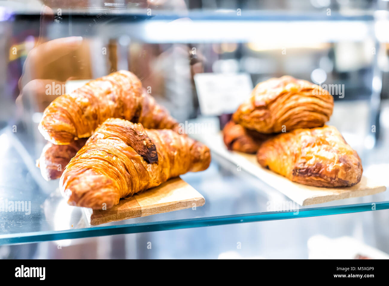 Closeup of plain butter golden baked crisp croissants on glass shelf ...