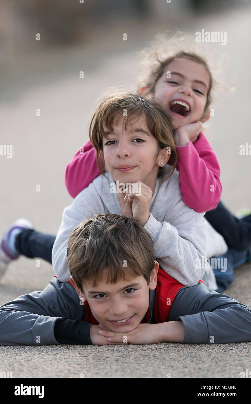 Three children lying on the floor one on top of the other. Horizontal ...