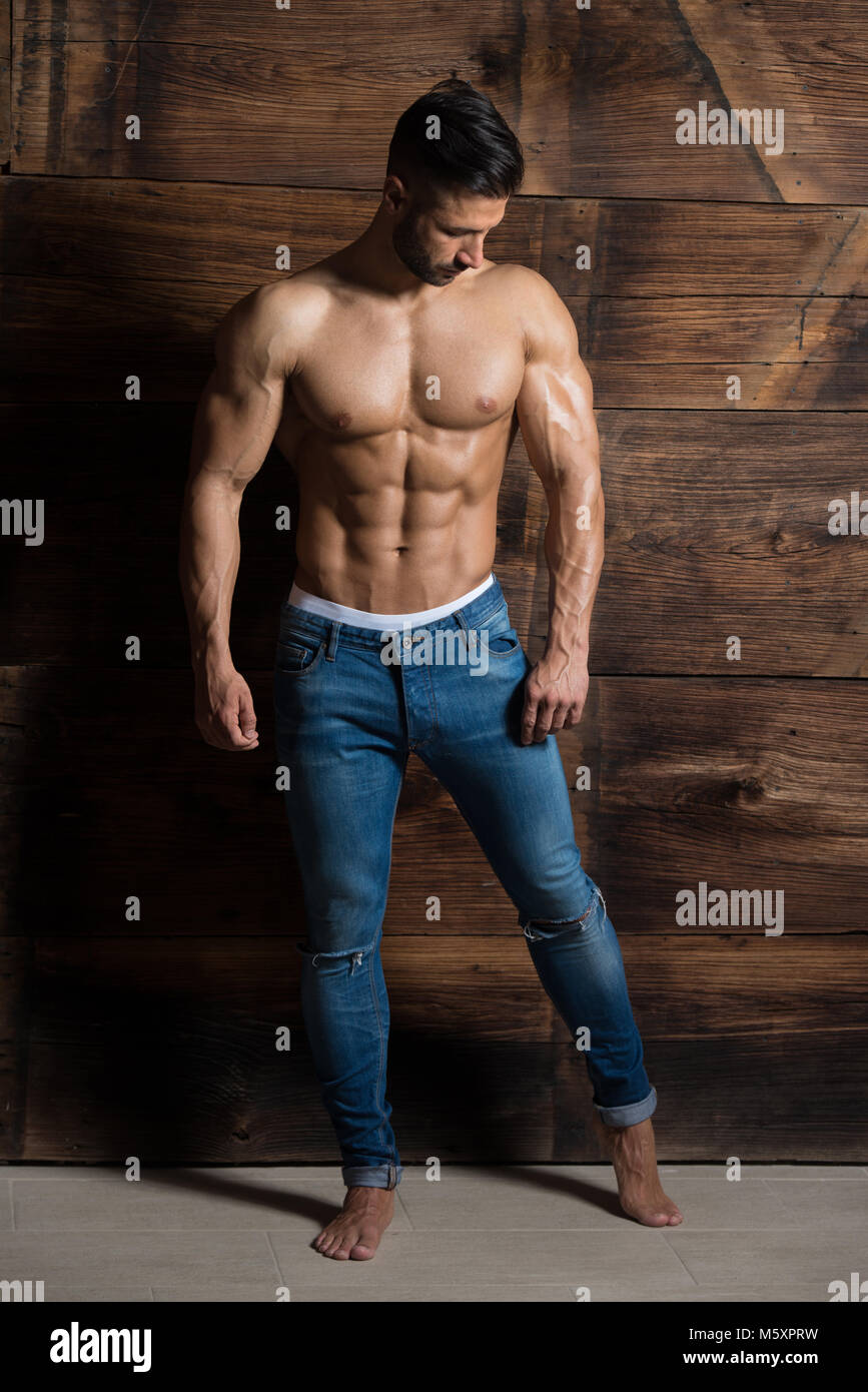 Healthy Young Man Standing Strong Against a Wooden Wall and Flexing ...