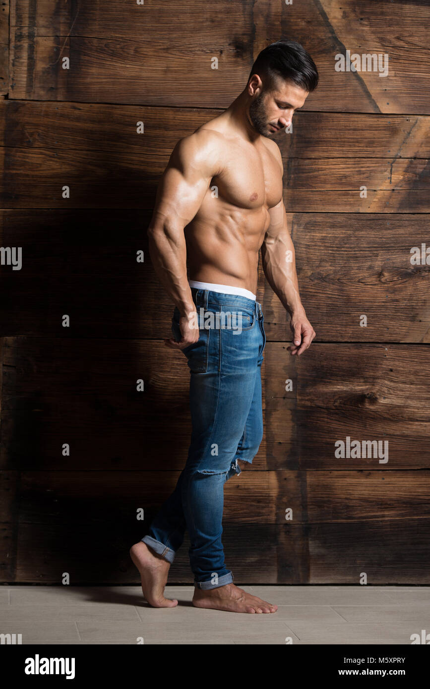 Healthy Young Man Standing Strong Against a Wooden Wall and Flexing ...