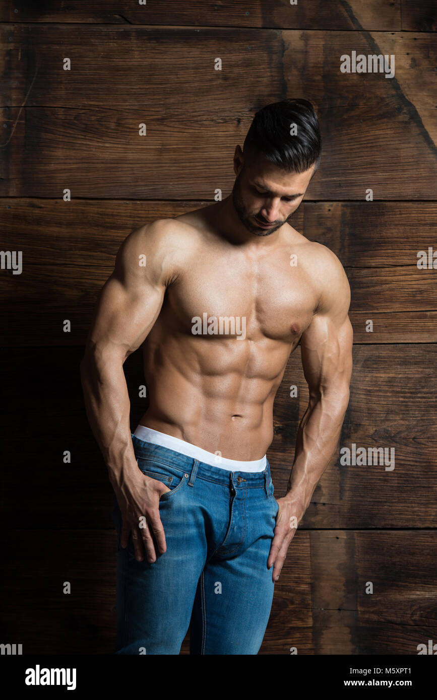 Healthy Young Man Standing Strong Against a Wooden Wall and Flexing ...