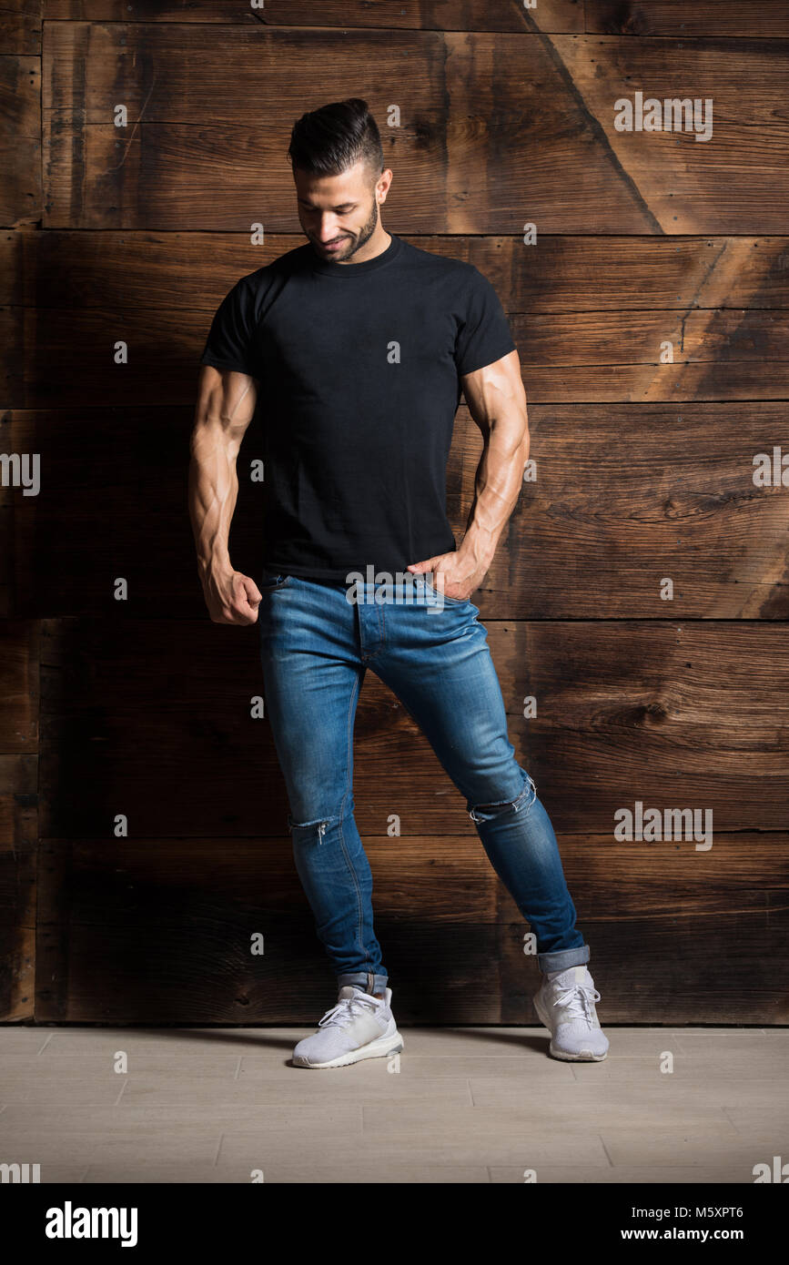Healthy Young Man Standing Strong Against a Wooden Wall and Flexing ...