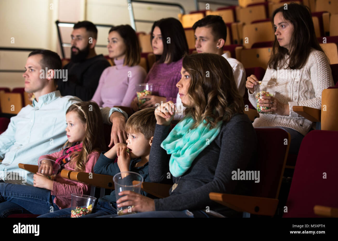 Group of people eating popcorn while watching film in cinema Stock ...
