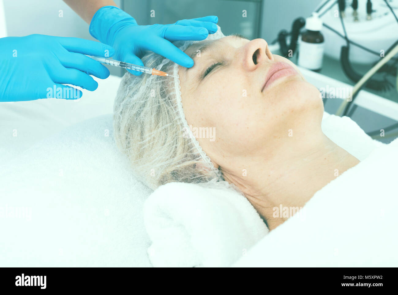 Young female doctor using injection in beauty procedures to woman ...