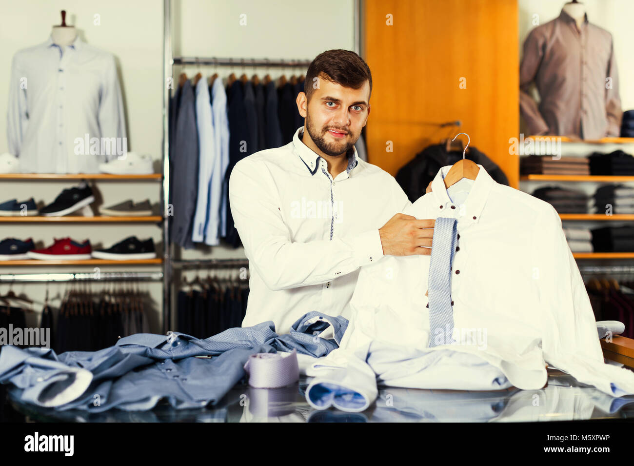 Smiling male shopping assistant demonstration shirt in men shop Stock ...