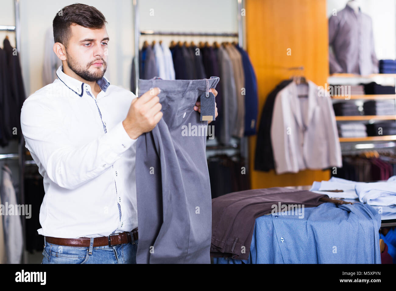 Portrait of businessman buying new pair of pants in men store Stock ...