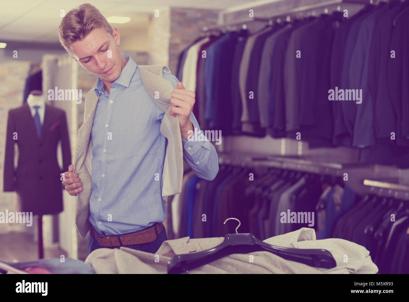 Portrait of buyer man choosing business style waistcoat in the shop ...