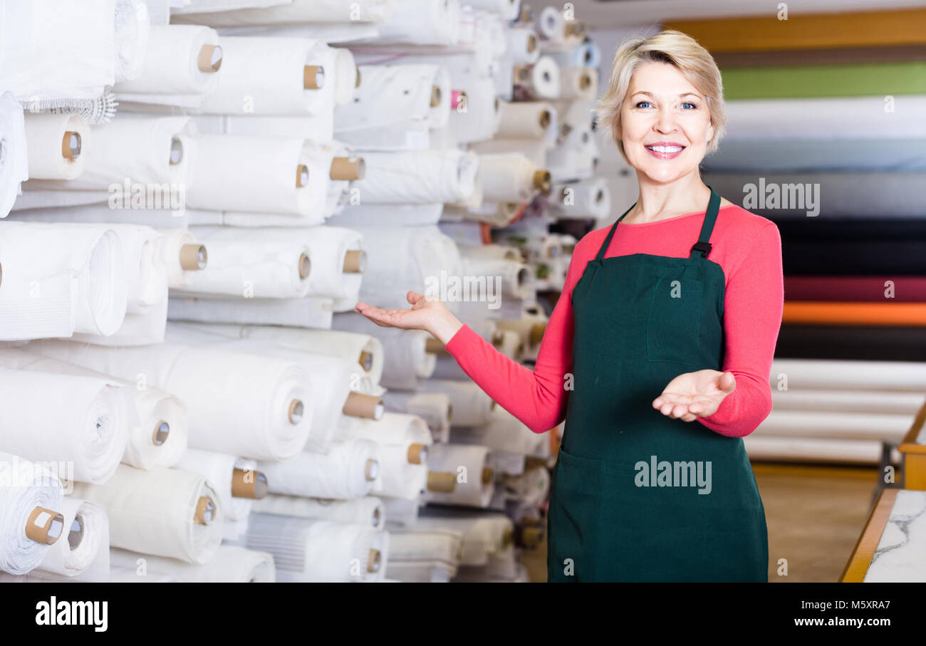 happy russian female shop assistant demonstrating assortment at textile ...