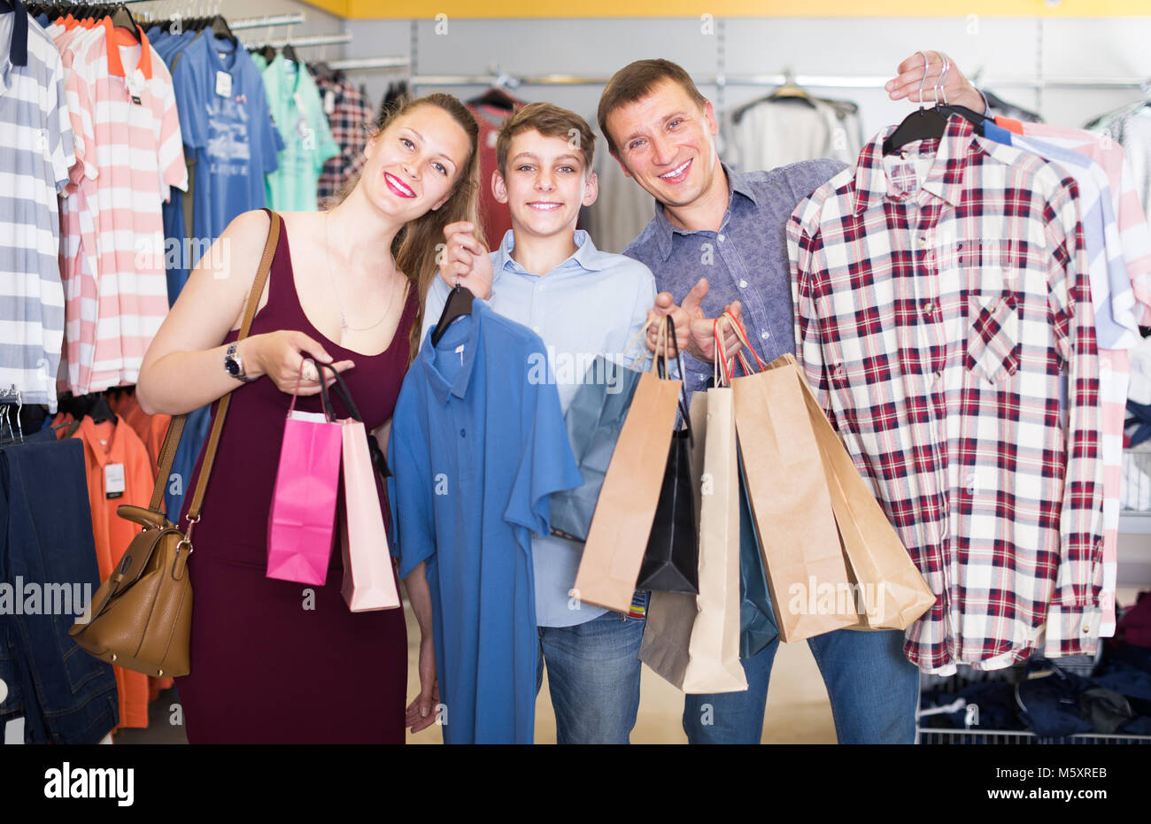 Cheerful family display packages with clothes in a boutique Stock Photo ...