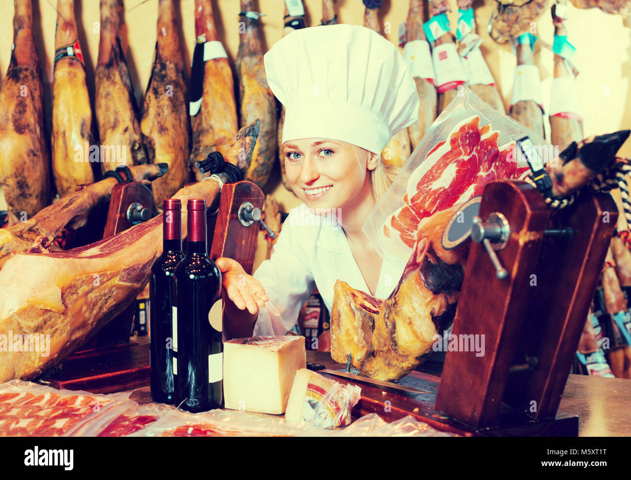 glad woman in uniform working with fresh meat in counter on market ...