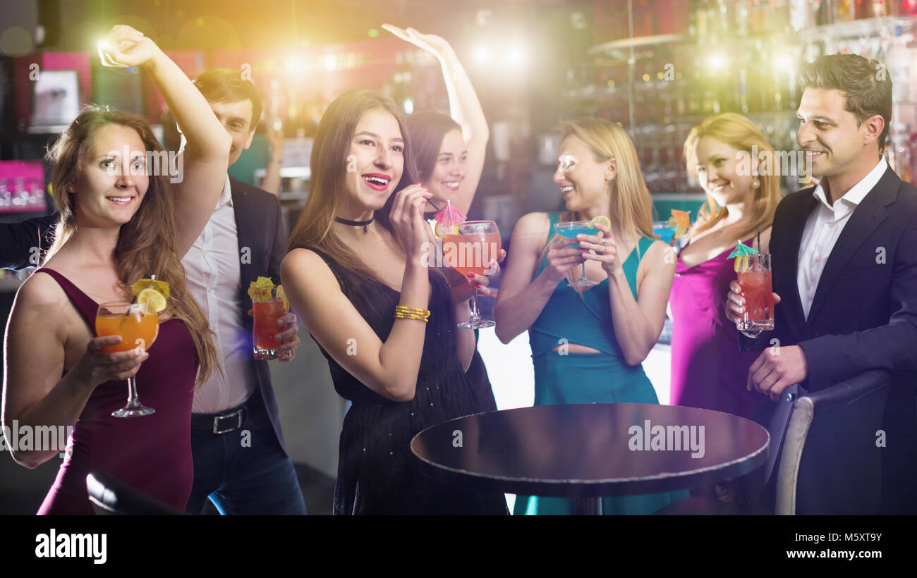 Happy positive colleagues dancing on corporate party with cocktails in ...