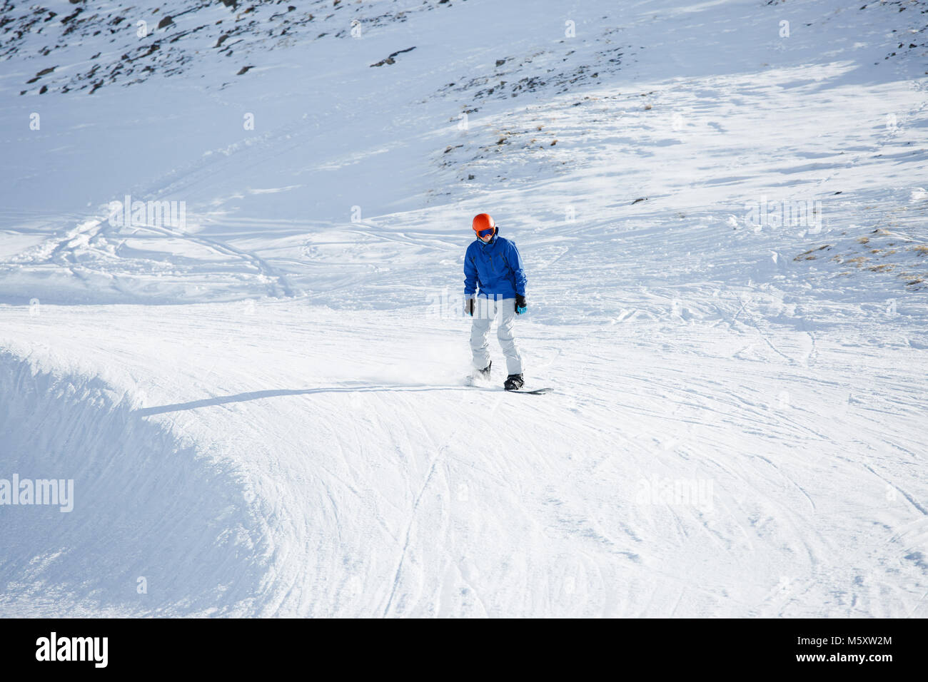 Photo of man in helmet riding snowboard from snowy slope Stock Photo ...