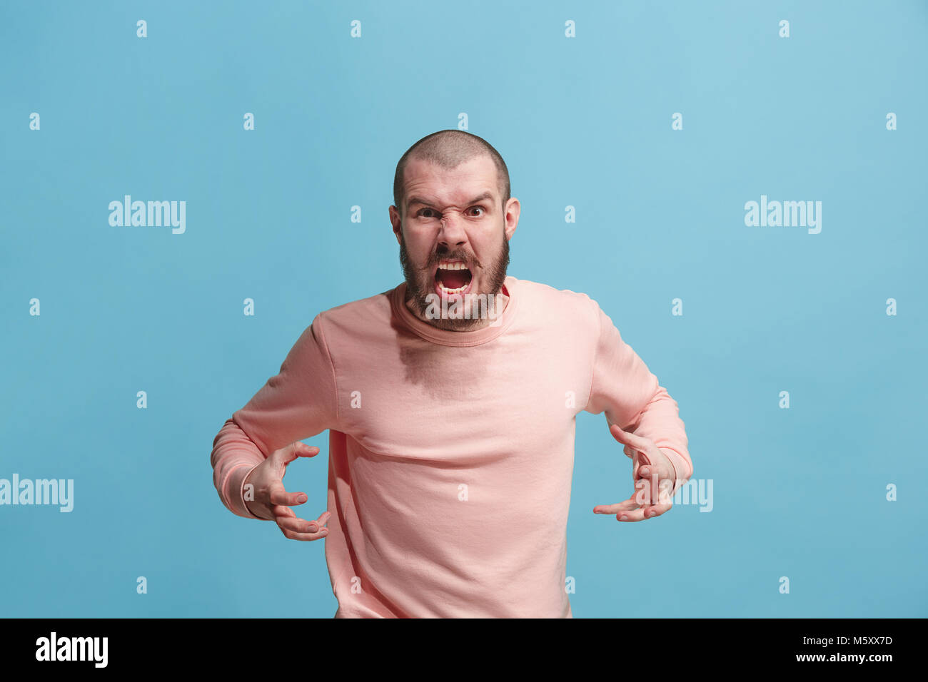 The young emotional angry man screaming on blue studio background Stock ...
